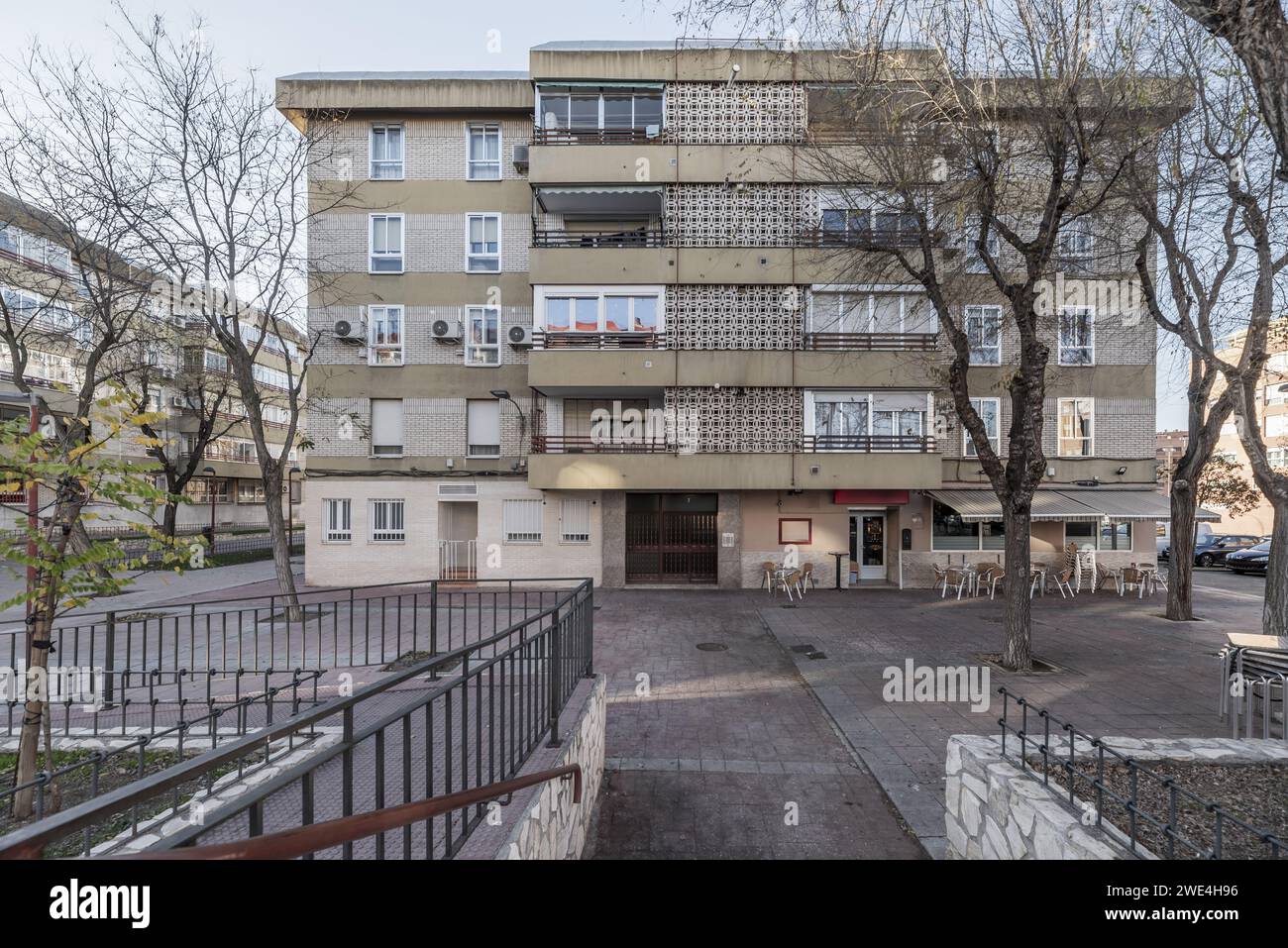 Facade of a building within an urban park with clear areas, trees and ...