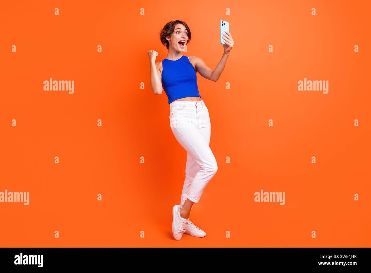 Full length photo of delighted pretty person use smart phone raise fist ...