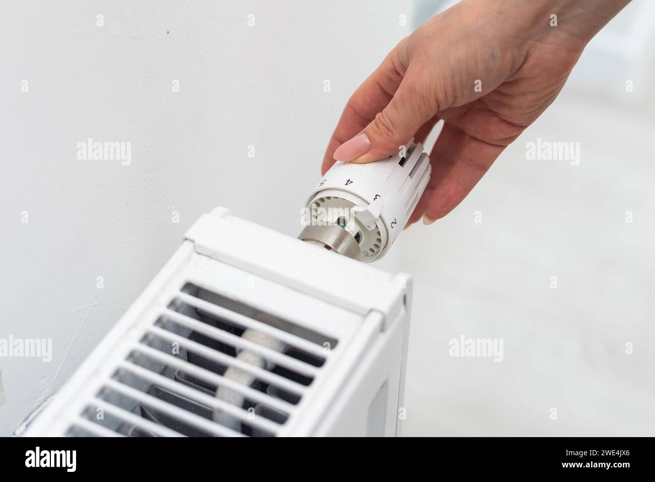 Heat radiator knob. Woman hand adjusting temperature on heating ...
