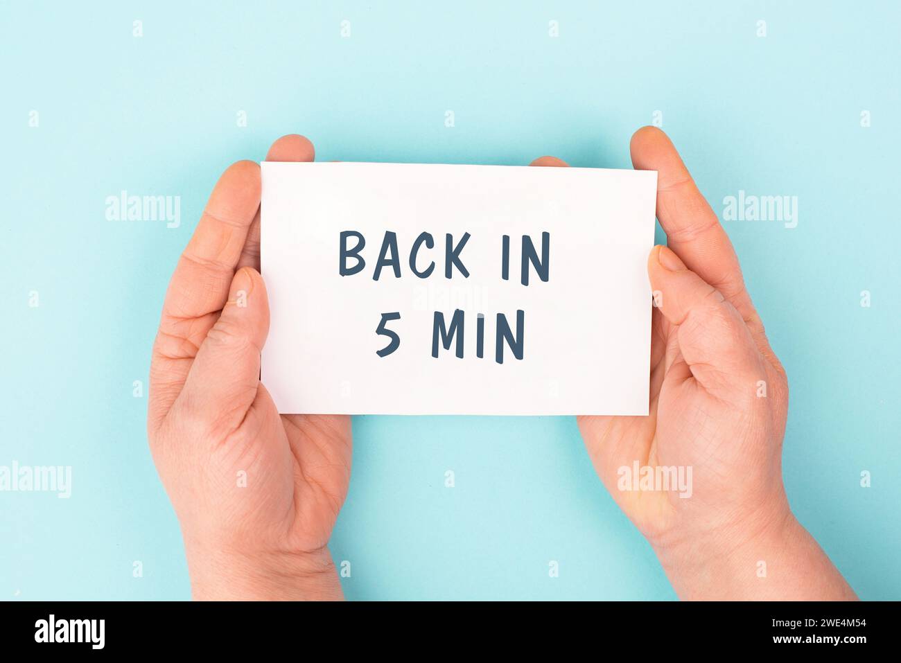 Back in 5 min is standing on a paper, hands hold message, working break ...