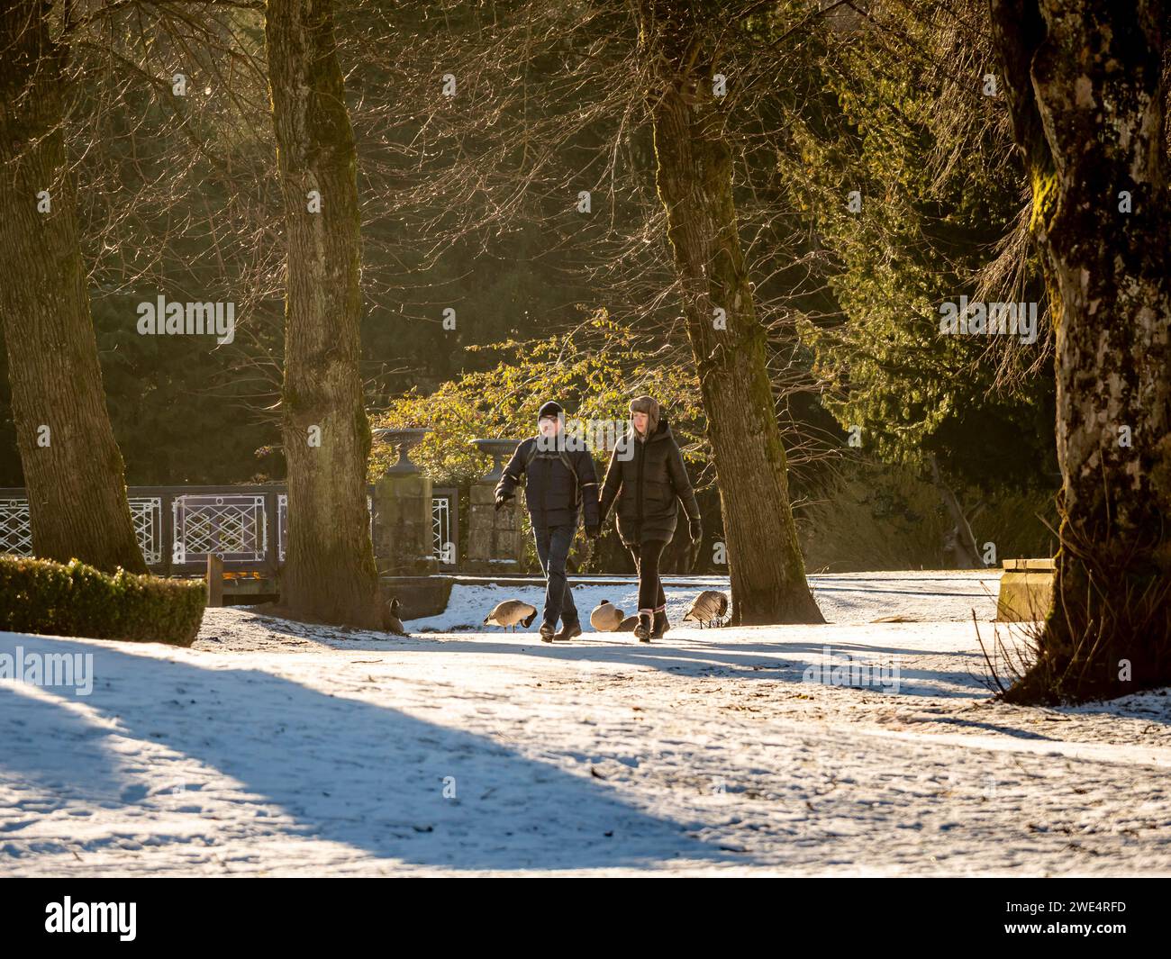 Couple wearing warm winter clothes walking through a snow covered ...