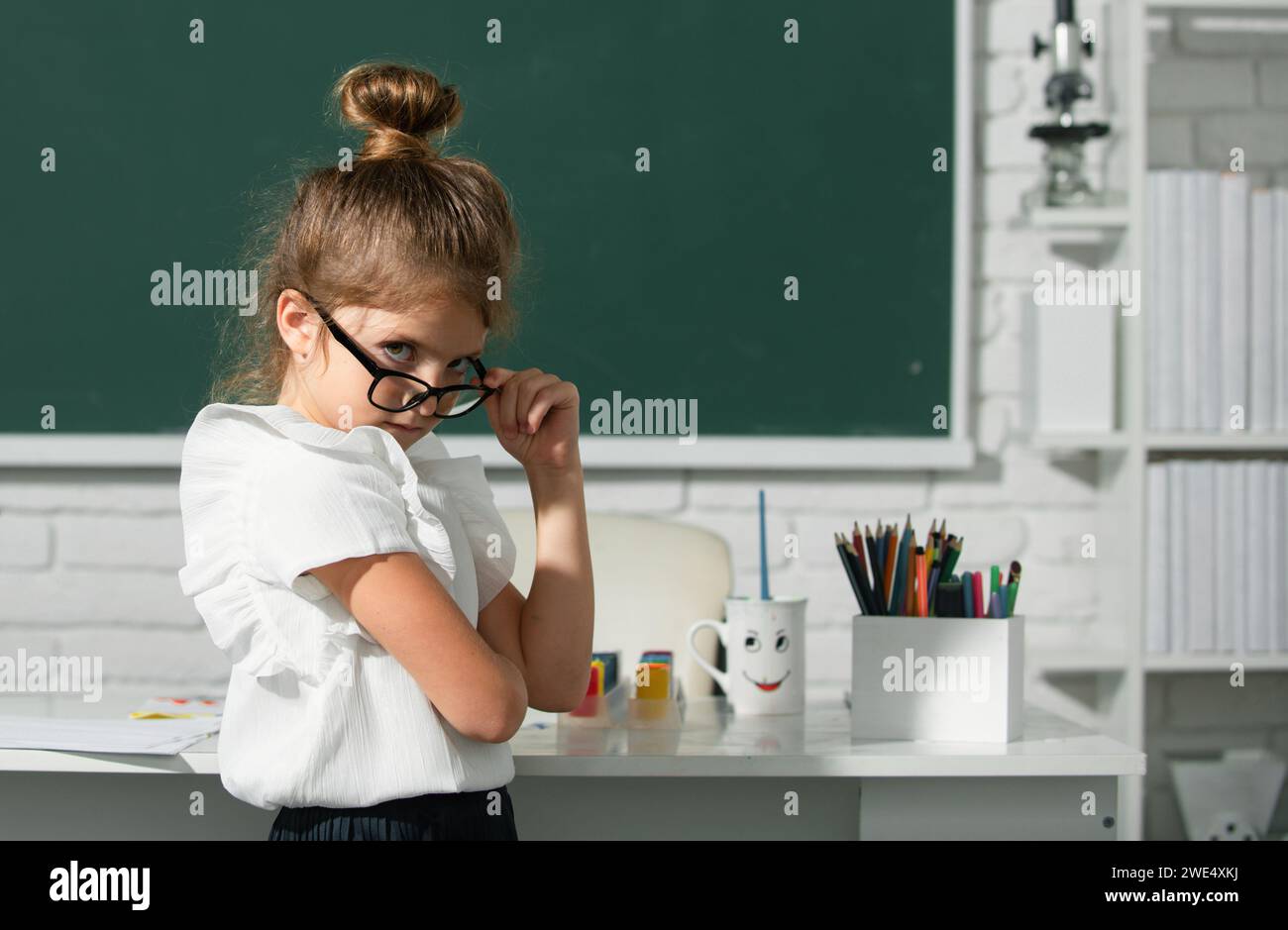Nerd school girl in glasses on chalkboard. Portrait of funny pupil girl ...