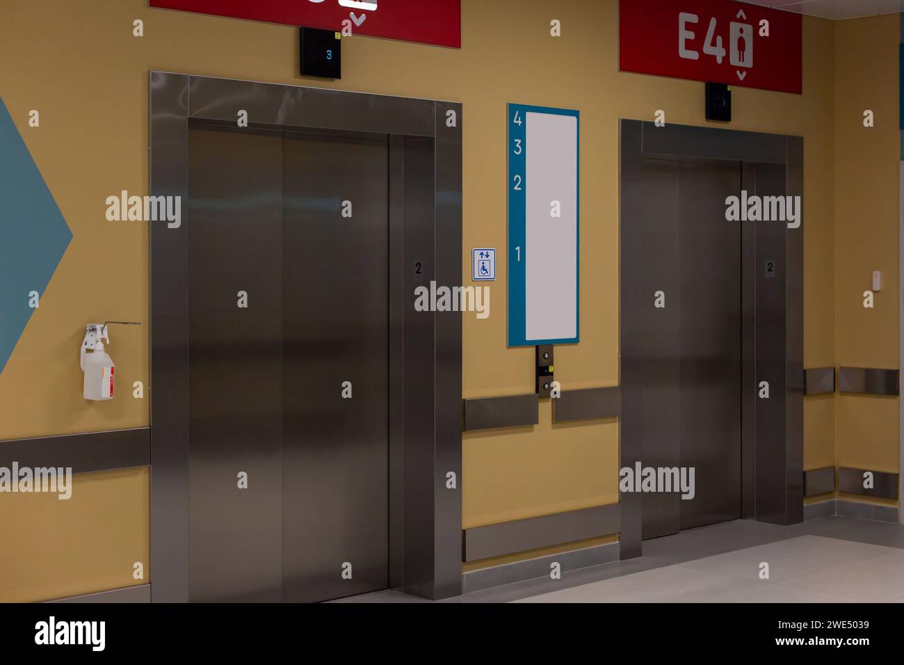 Modern elevator doors with red directional signs in a corridor Stock ...