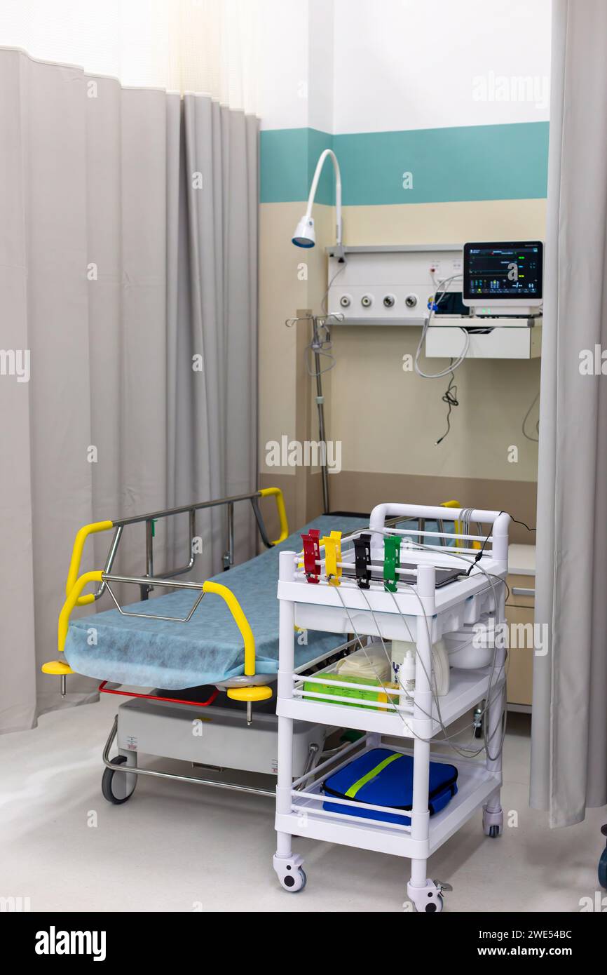Hospital room setup with an empty patient bed, a medical trolley, and a ...