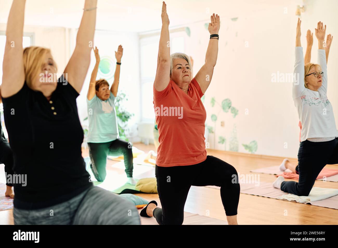 A group of senior women engage in various yoga exercises, including ...
