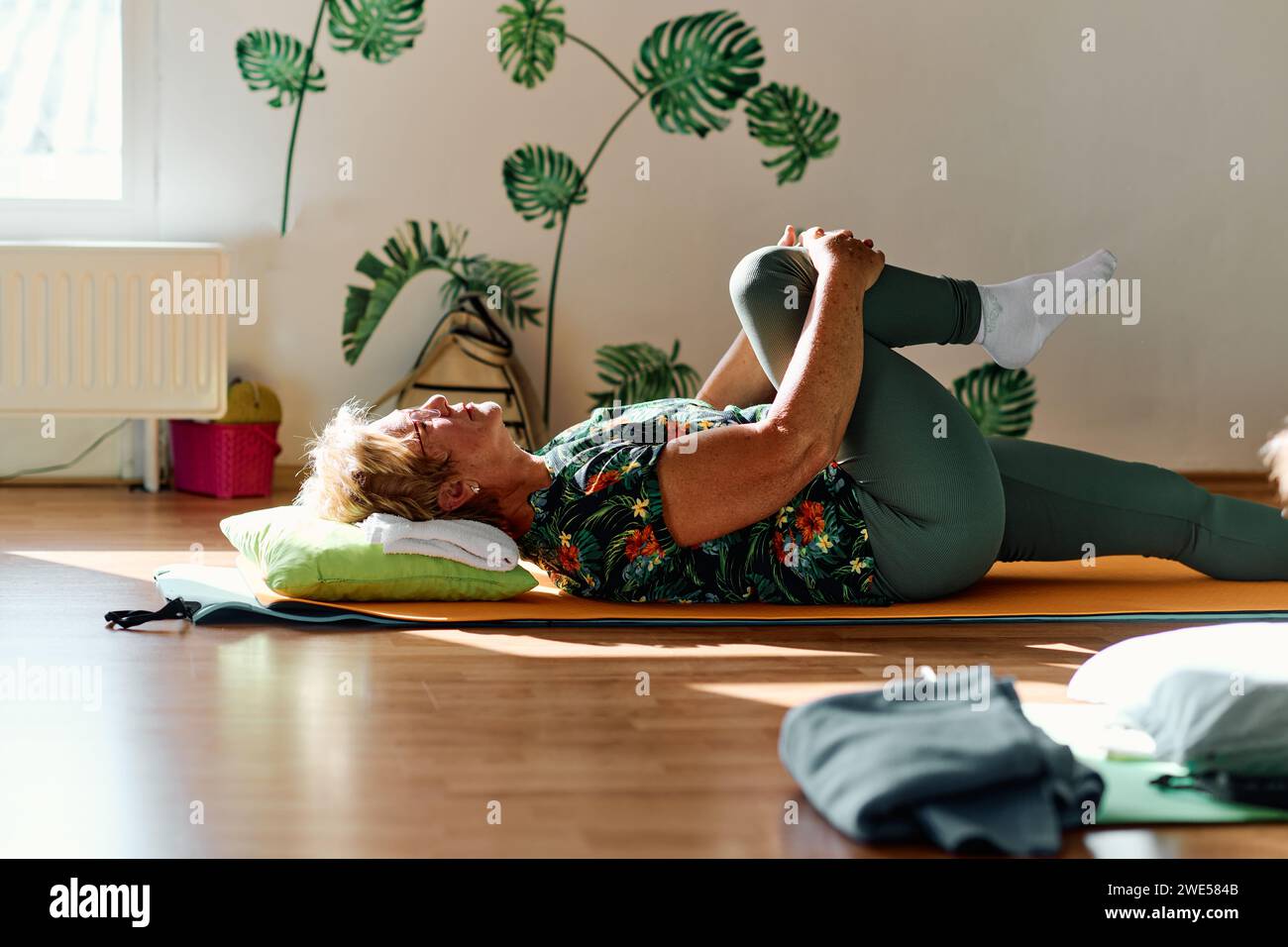 In a sunlit space, a senior woman gracefully practices rejuvenating ...