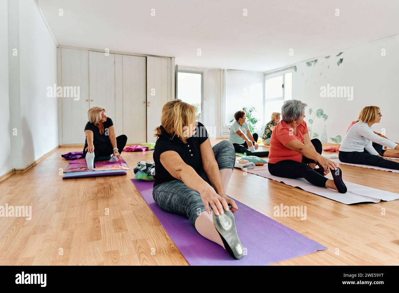 A group of senior women engage in various yoga exercises, including ...