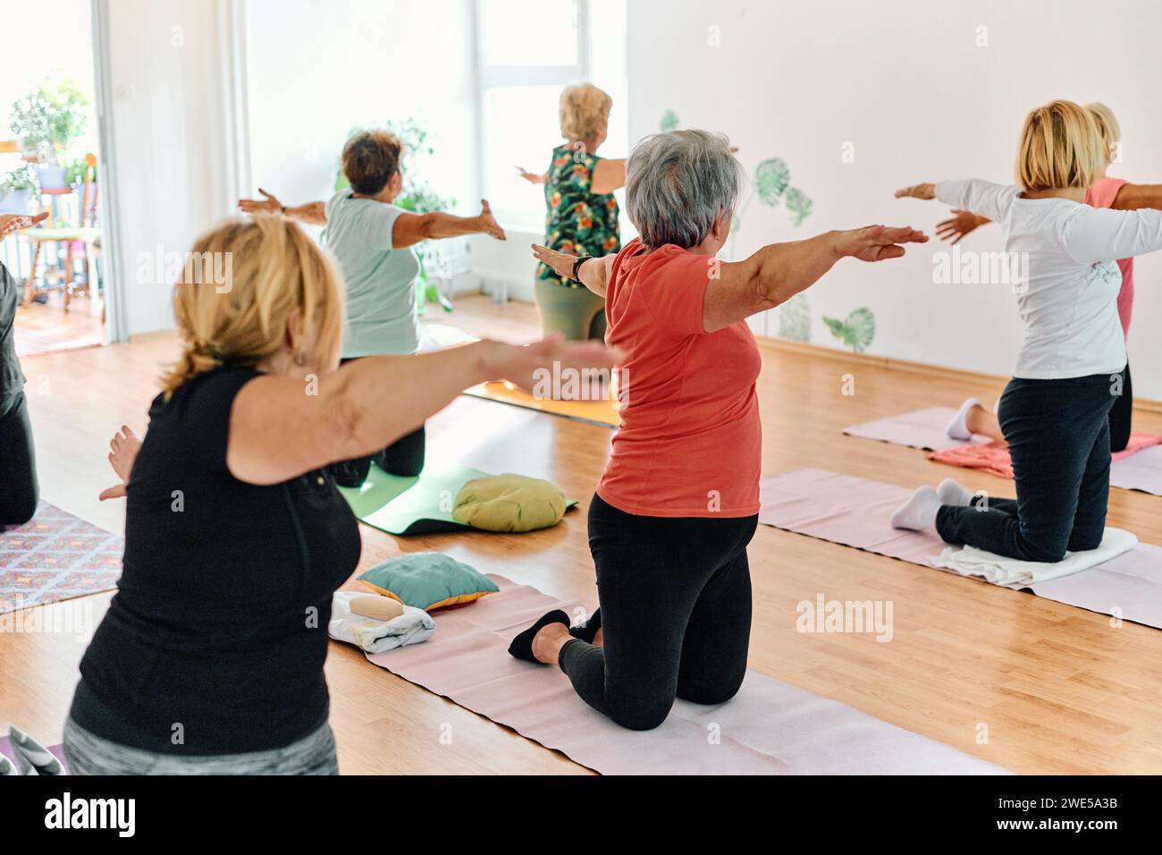 A group of senior women engage in various yoga exercises, including ...
