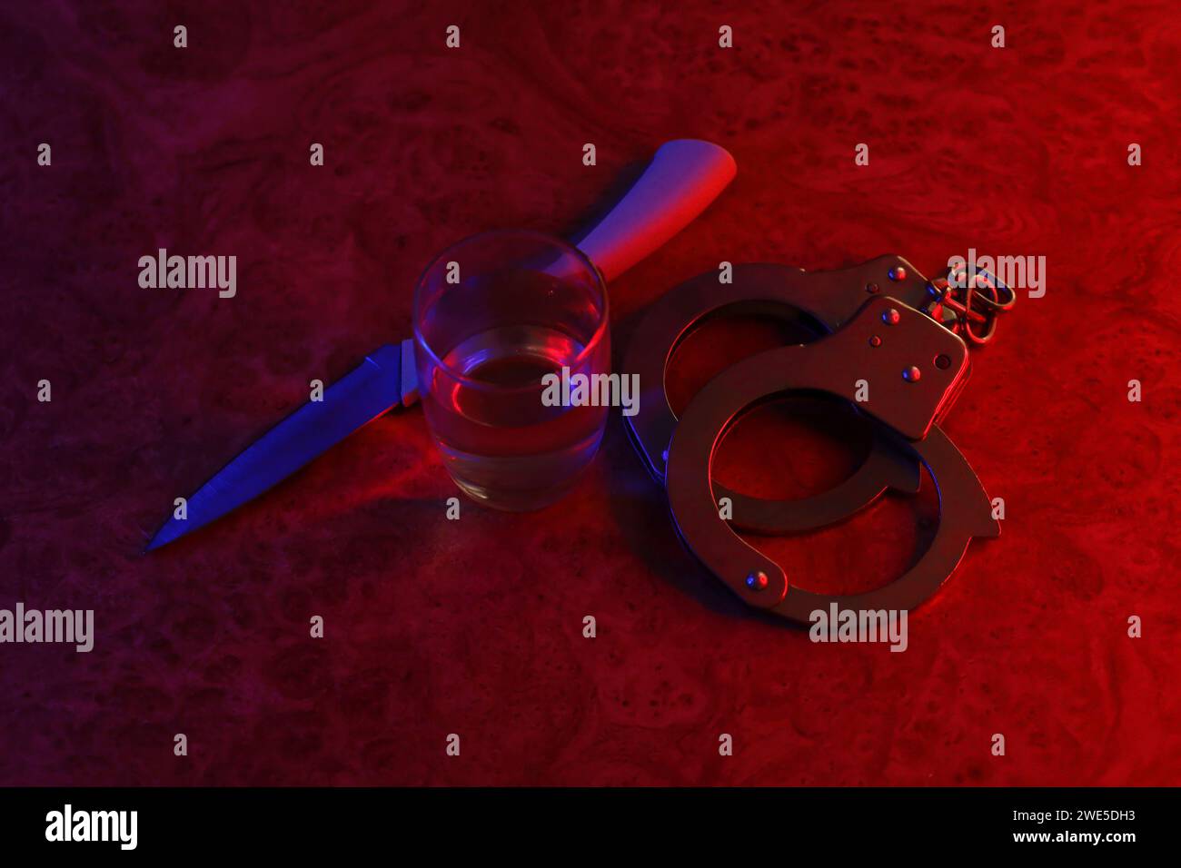 Glass with vodka alcohol drink, knife and handcuffs. Concept of ...