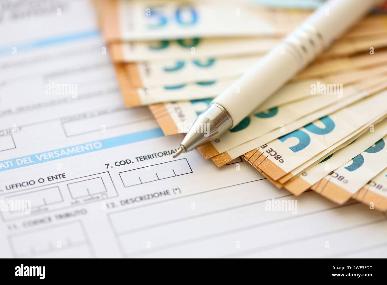 Filling italian tax form process with pen and euro money bills close up ...