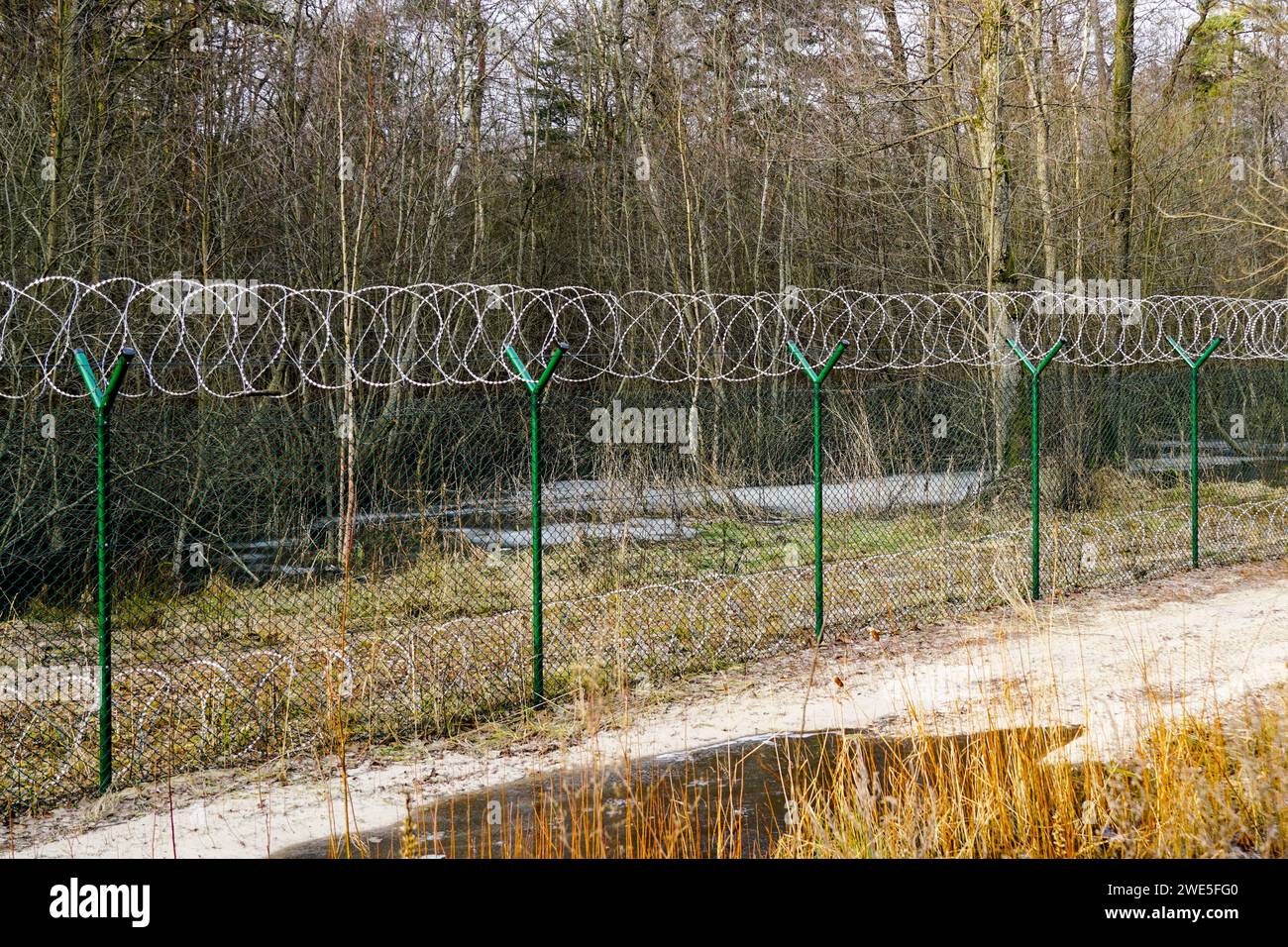A green metal mesh fence with coiled barbed wire around the restricted ...