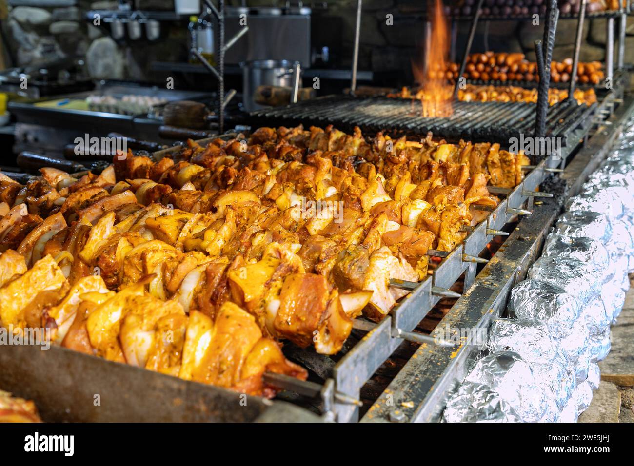 Shish kebab skewers, baked potatoes and grilled Polish sausages at a ...