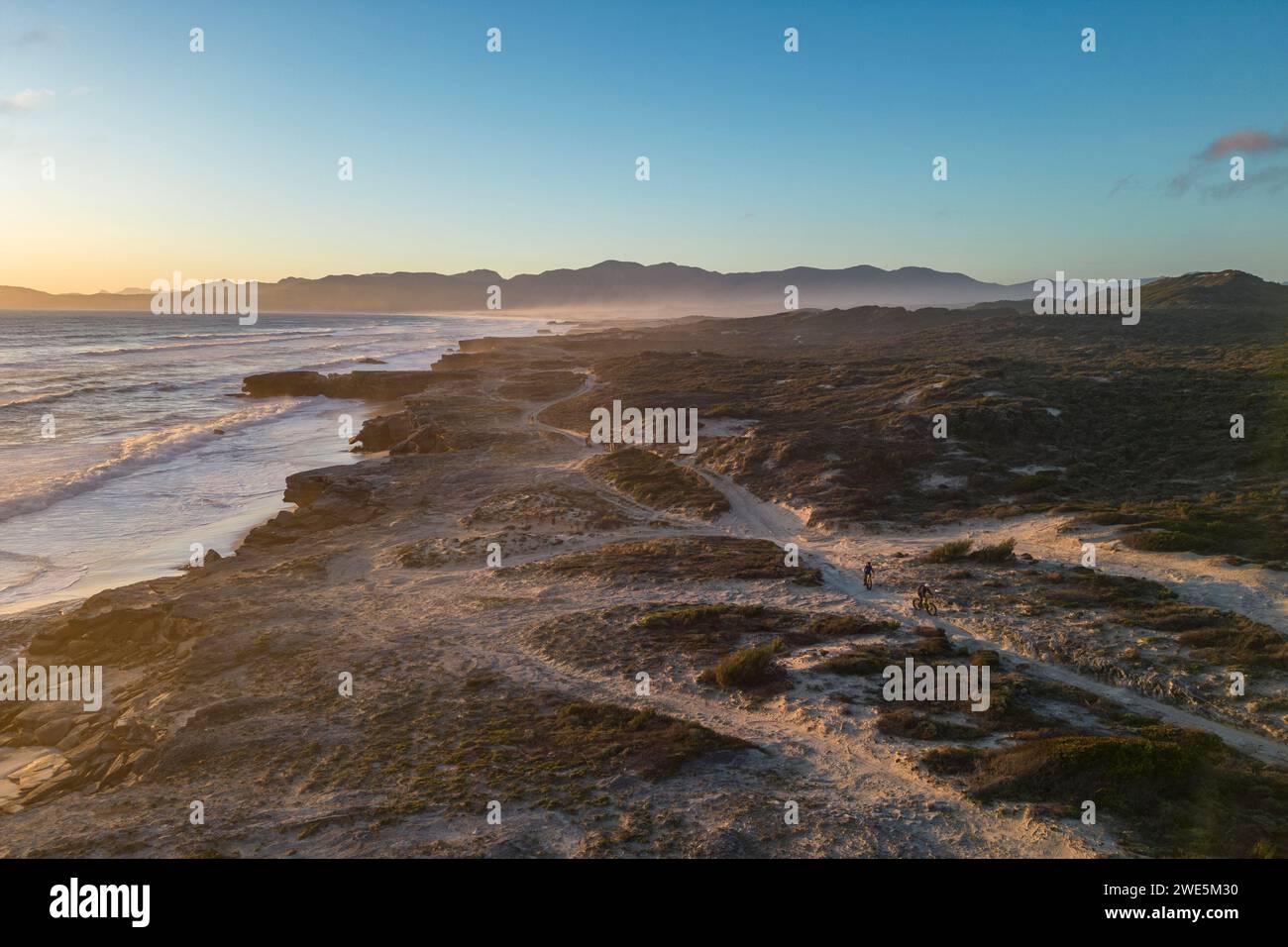 Aerial view of people riding fat tire bicycles at sunset on sandy paths ...