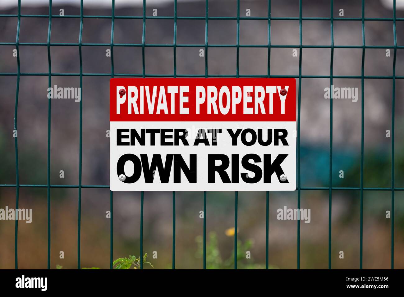 Red an white warning sign on a fence stating in "Private property ...