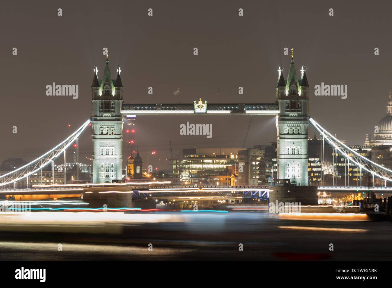 Tower Bridge at night with small boats passing around leaving a ...