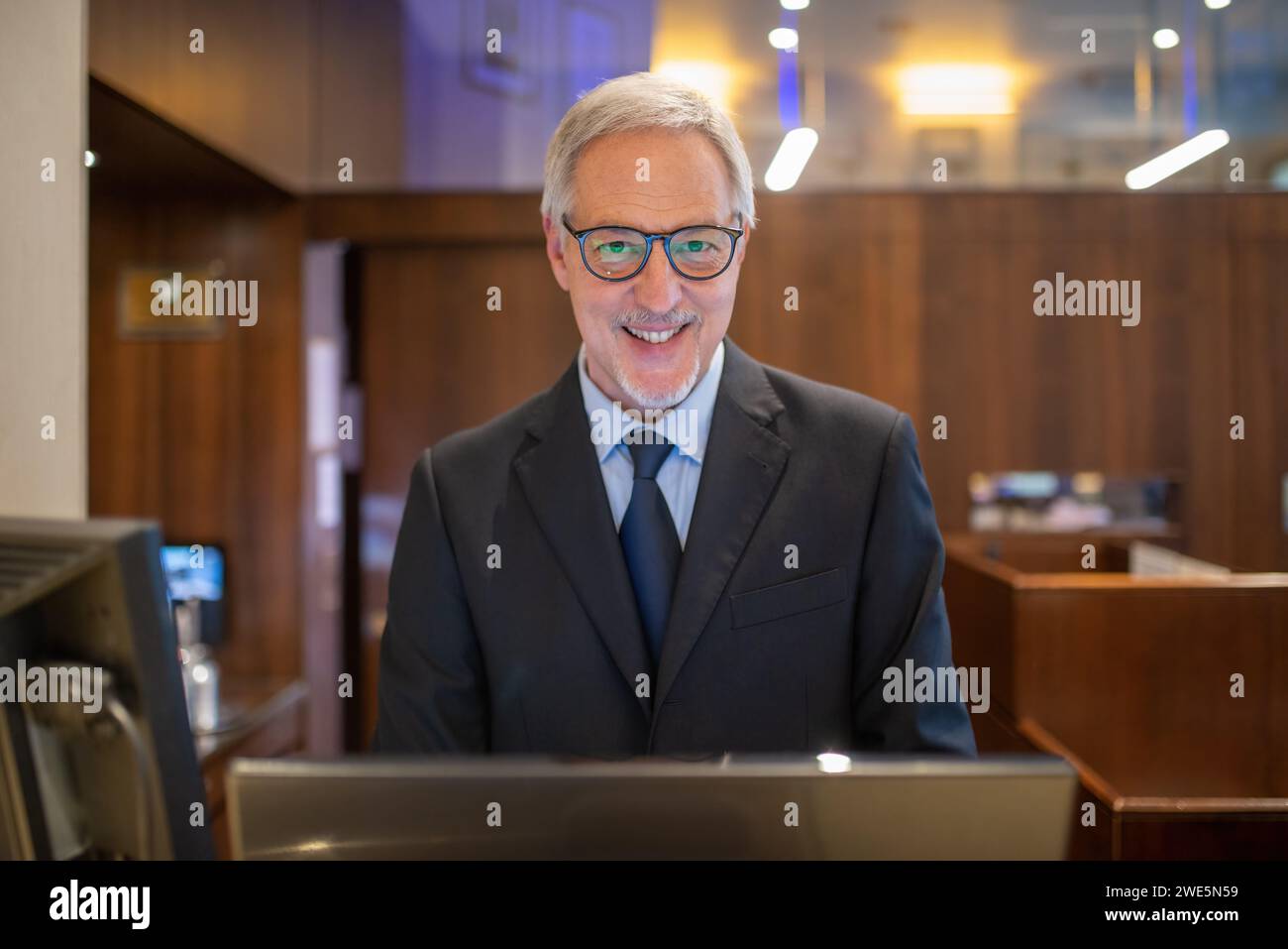 Smiling man at work in an hotel reception Stock Photo - Alamy
