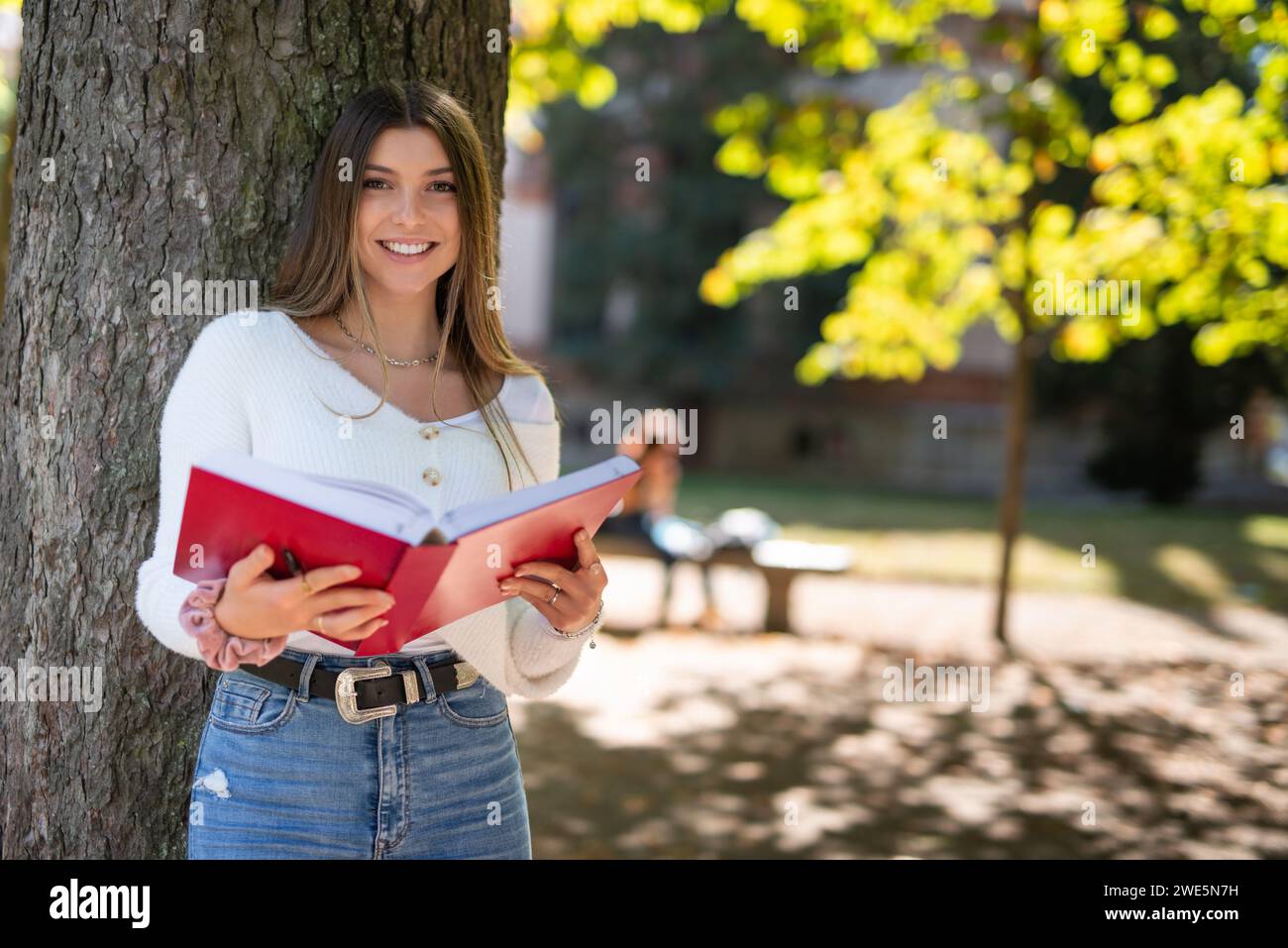 Female college student reading a book outdoor near a tree Stock Photo ...