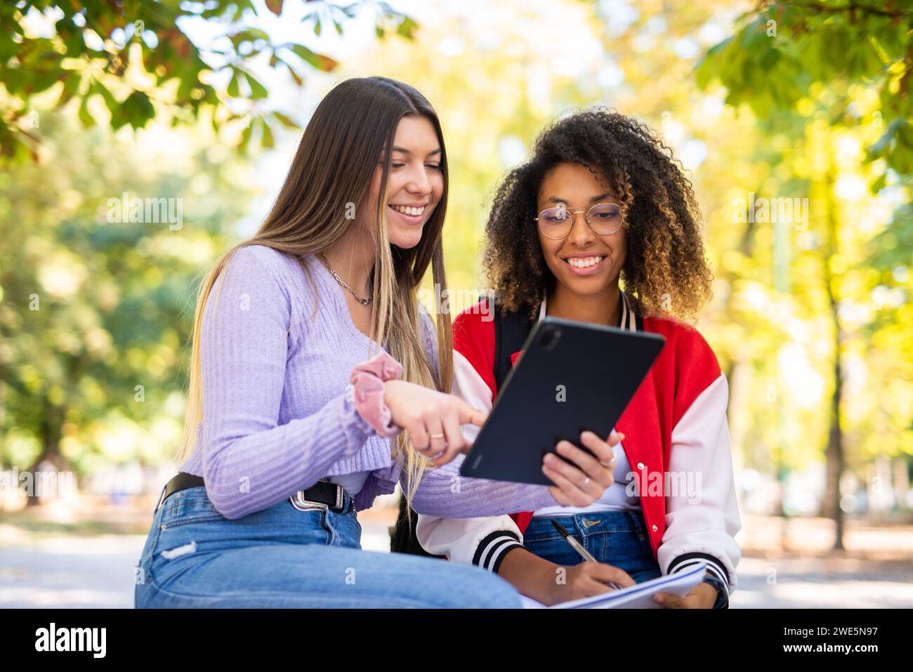 Female college students studying together in a park near their ...