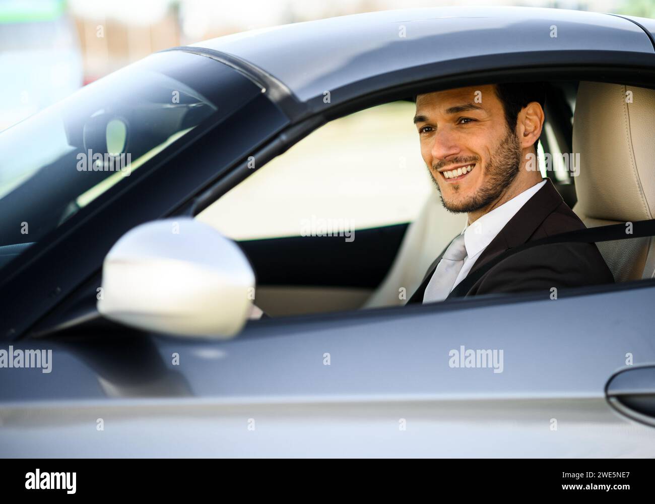 Successful young caucasian businessman confidently driving a modern ...