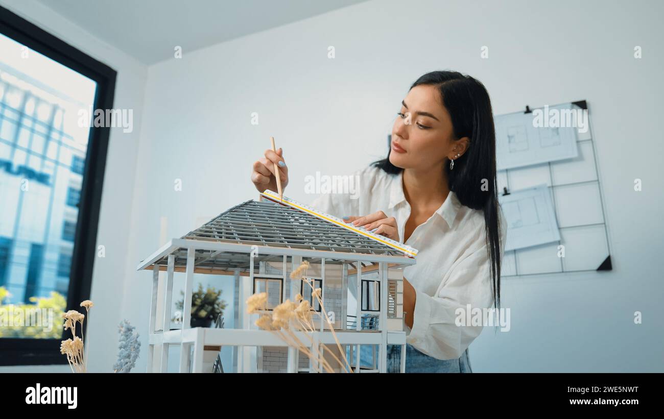 Professional young beautiful architect engineer using ruler and pencil measuring model roof ...