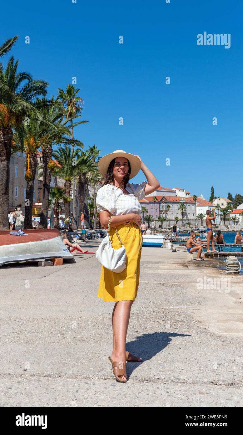 A woman in stylish summer clothes at the seafront with piers, palm ...