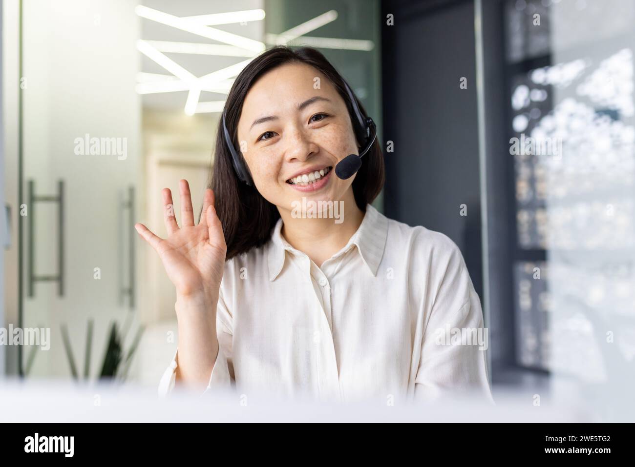 First person view of smiling asian woman in wireless headset with micro ...