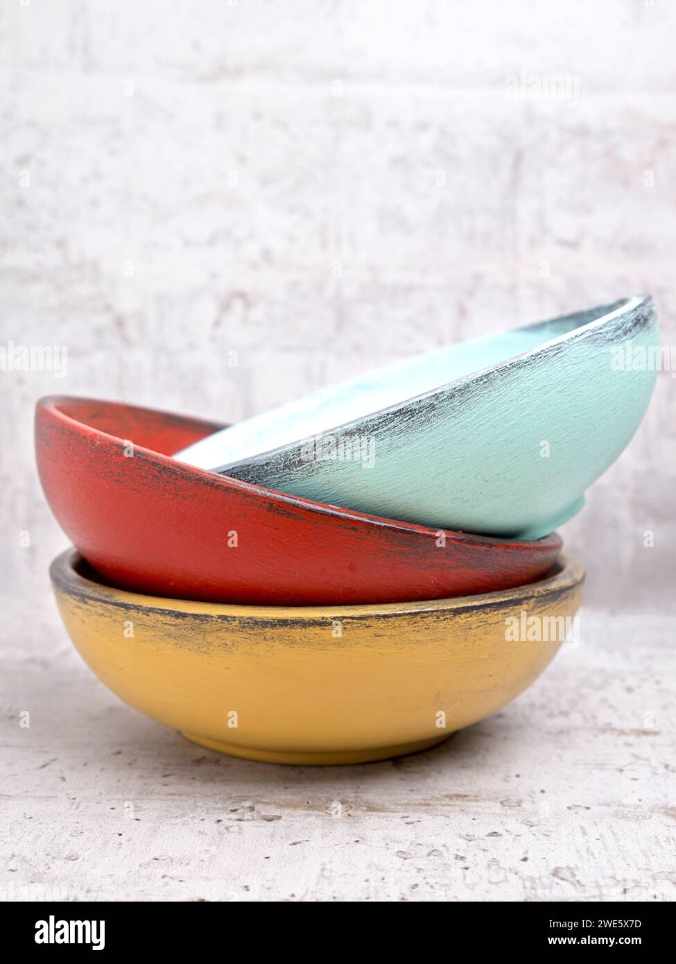 A studio photo of three multi colored wooden bowls stacked together ...