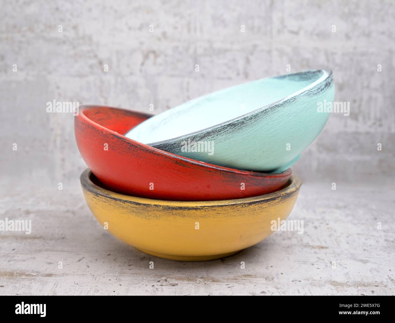 A studio photo of three multi colored wooden bowls stacked together ...