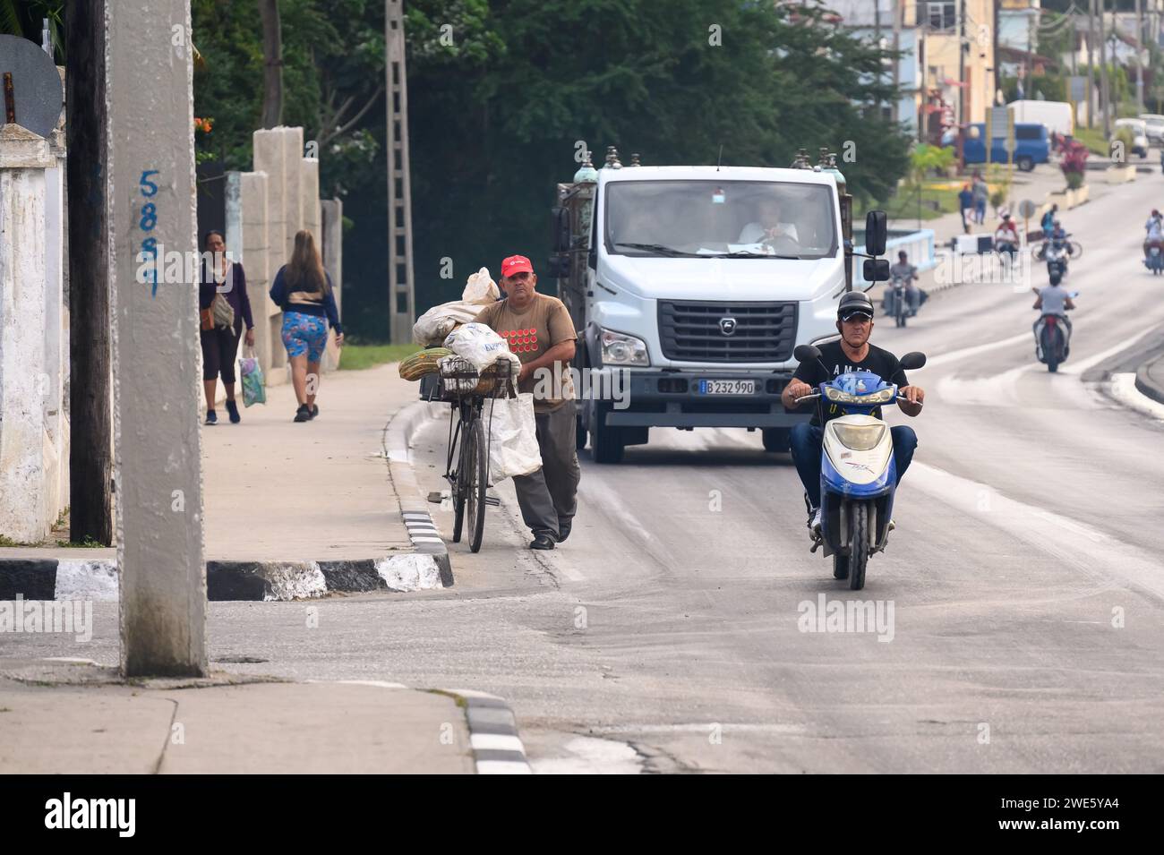 Morning traffic in the Central Road. A man driving an e-bike, a truck ...