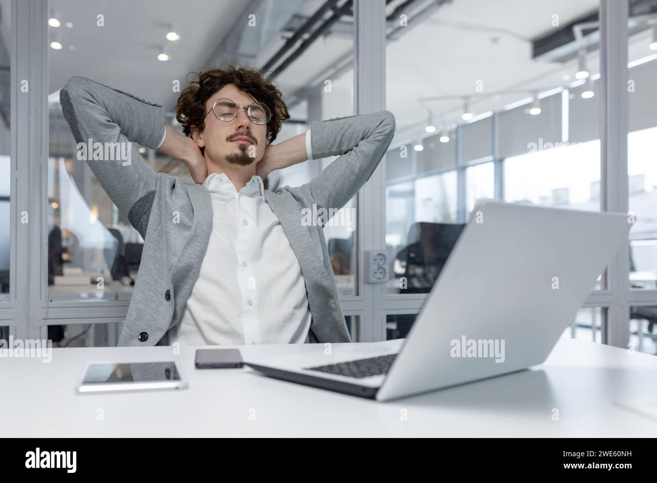 Adult male office worker at his desk takes a moment to unwind ...