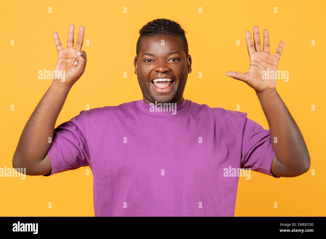 Cheerful black guy raising both hands showing number eight, studio ...