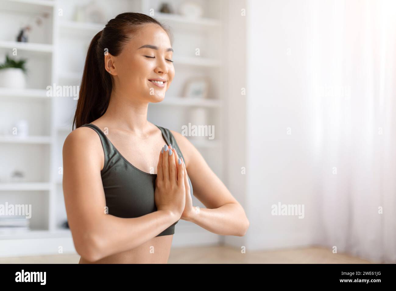 Beautiful asian woman practicing yoga with eyes closed and making ...
