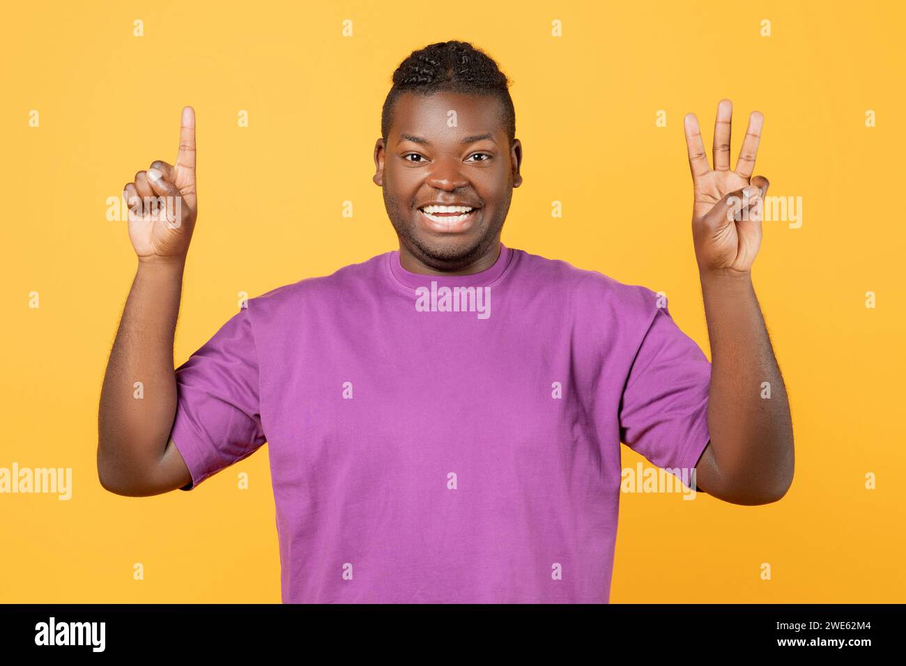 Toothy black guy raising both hands showing number four, studio Stock ...