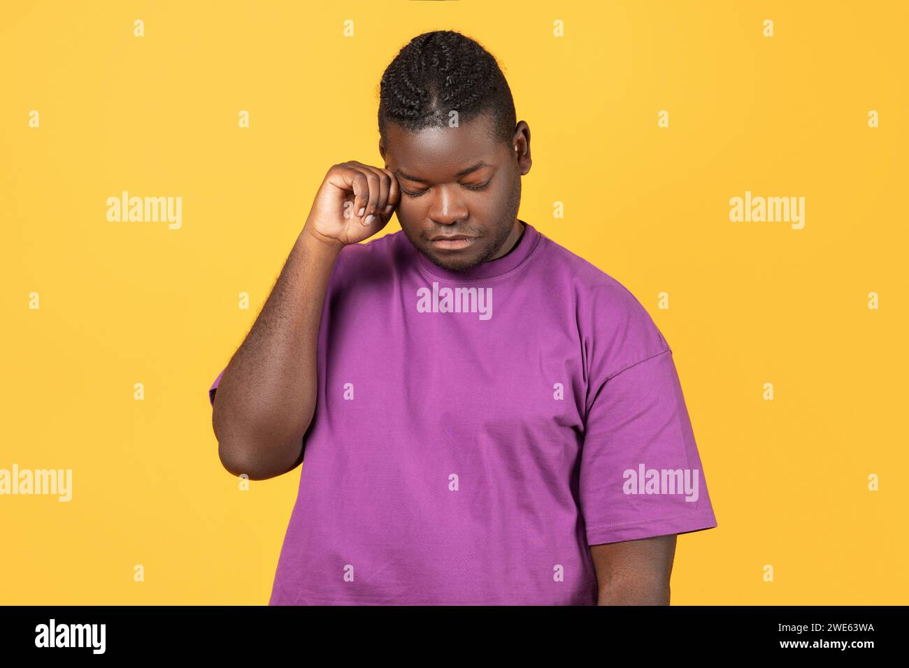 Distressed young black man wiping tears crying against yellow ...