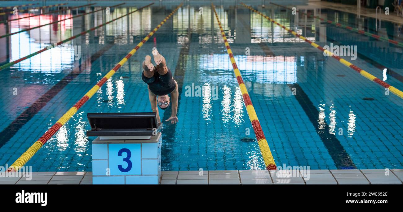Professional female swimmer preparing and jumping off the starting ...