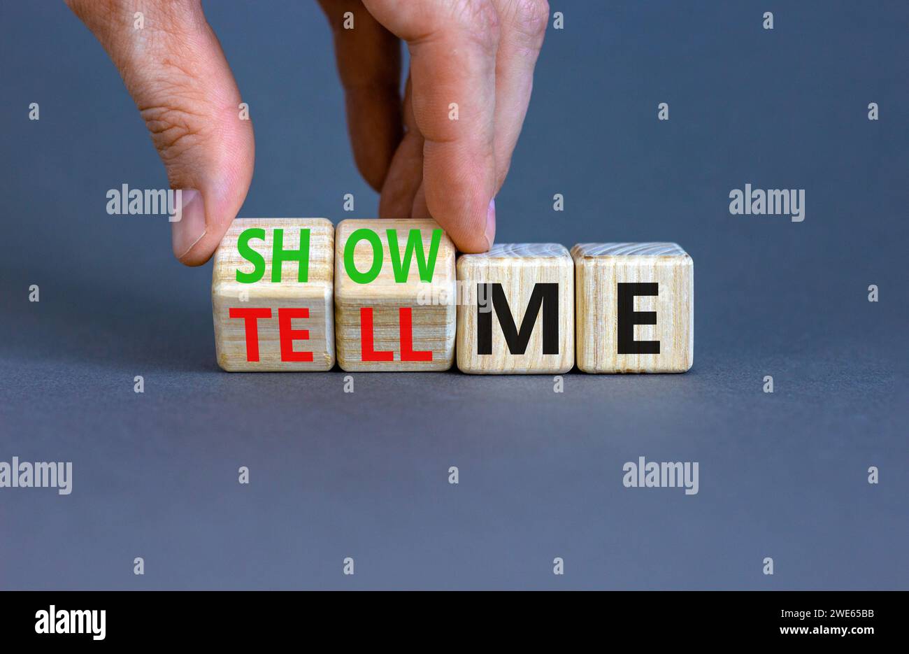 Tell or show me symbol. Businessman turns beautiful wooden cubes and ...