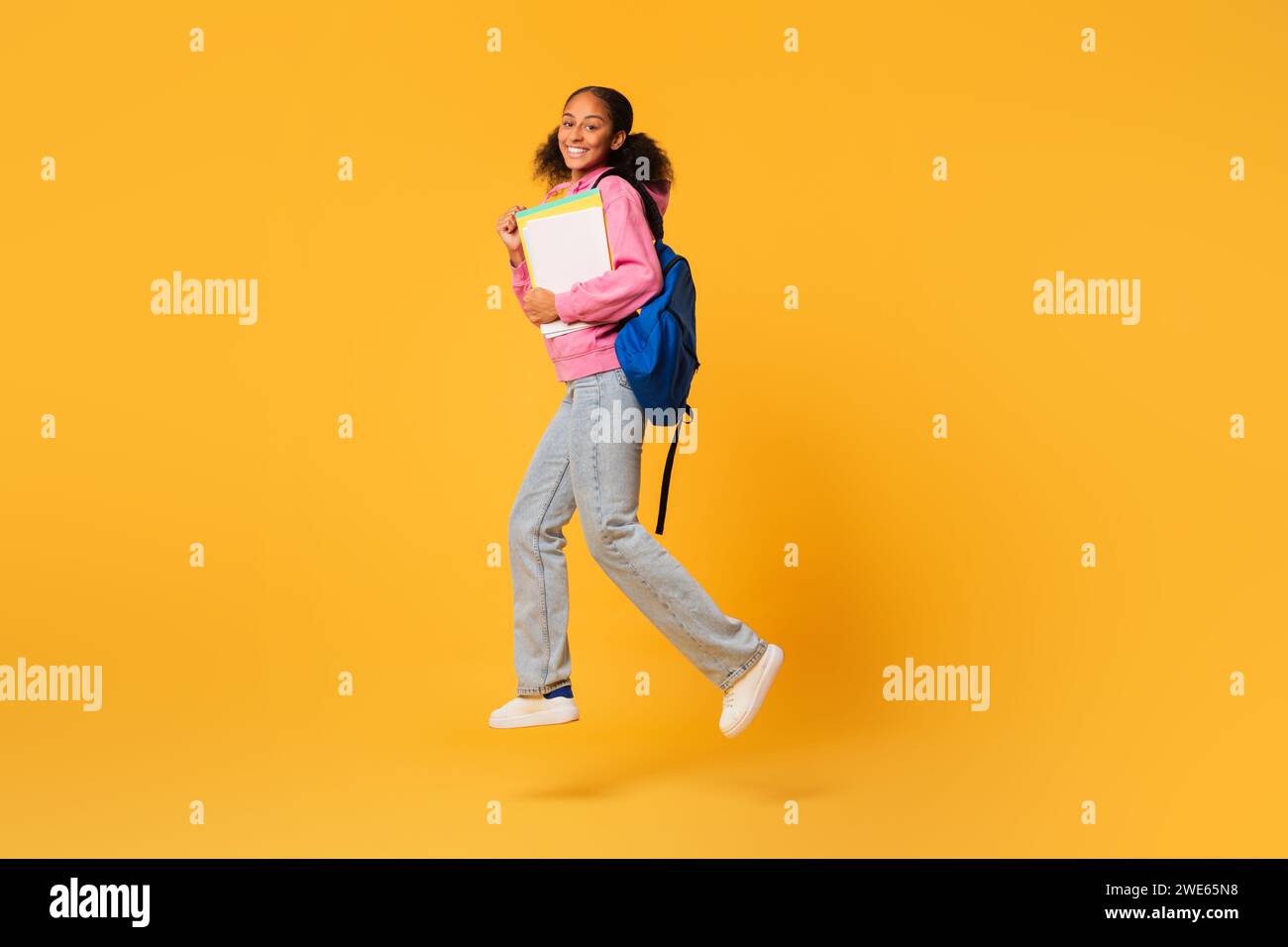 Happy black student girl jumping with backpack and workbooks, studio ...