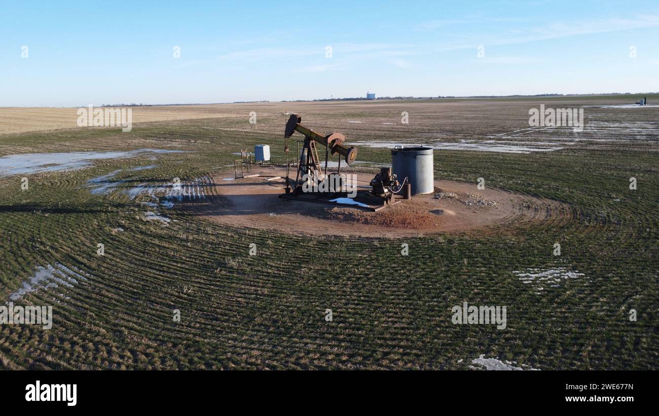 An oil well situated on a compact dirt field adjacent to water storage ...