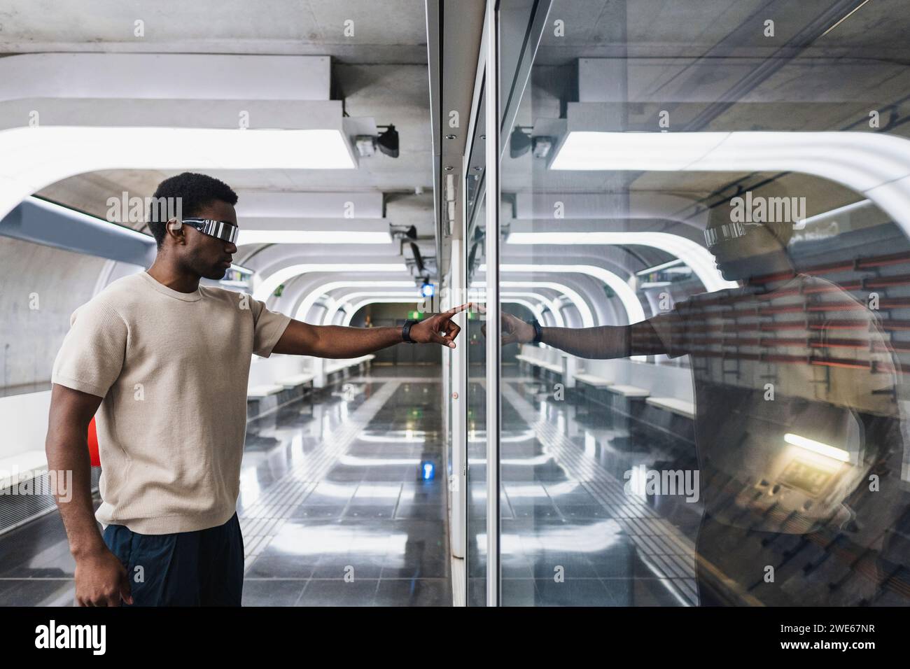 Young man with cyber glasses touching glass pane with his forefinger ...