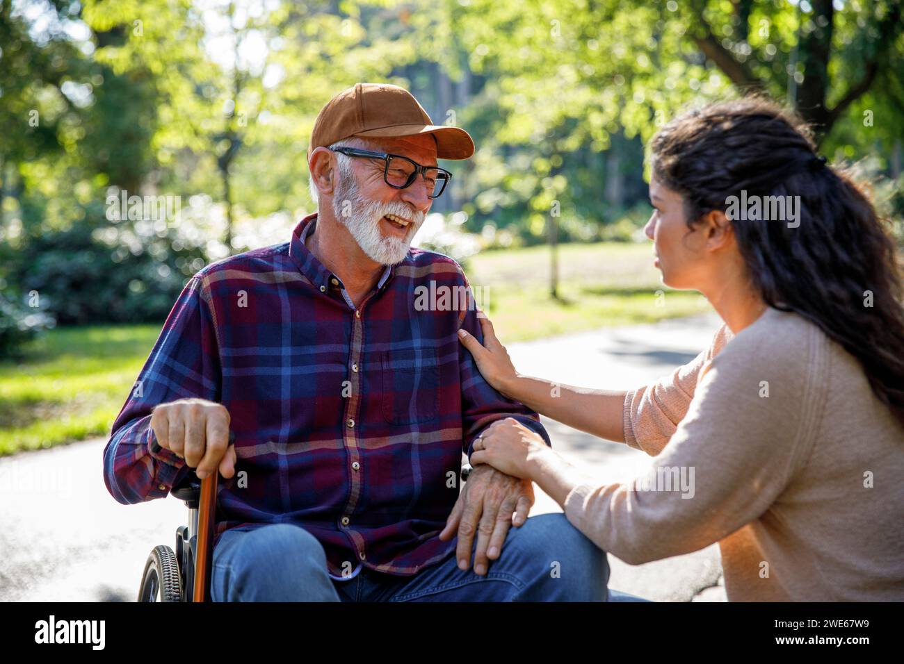 Happy retired senior man in wheelchair talking with social worker at ...