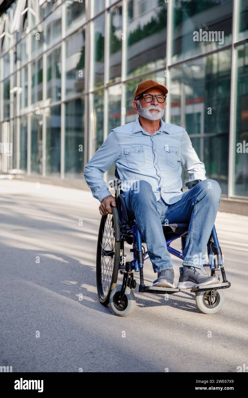 Retired senior man sitting in wheelchair on footpath Stock Photo - Alamy