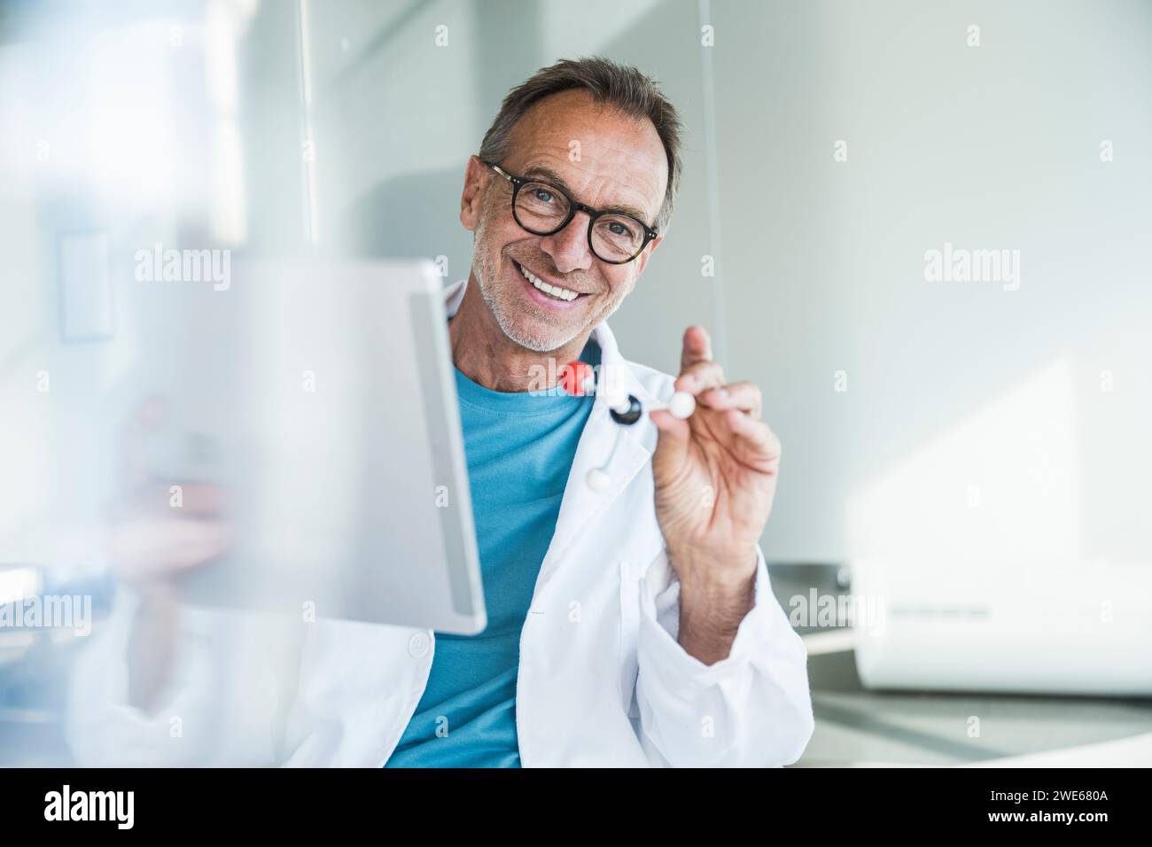 Happy senior man in lab coat holding tablet PC and molecular structure ...