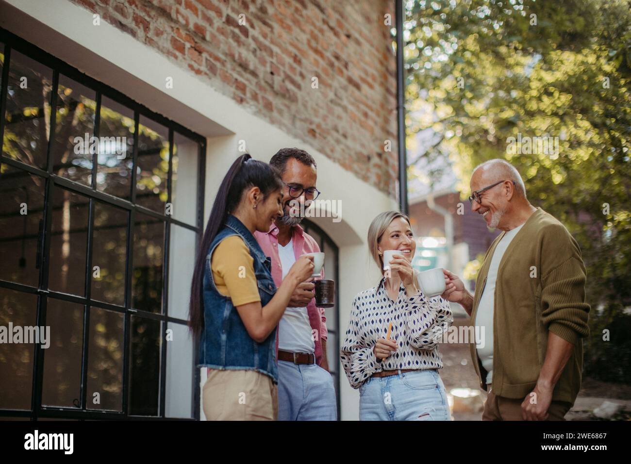 People at community meeting standing outdoors talking and drinking ...