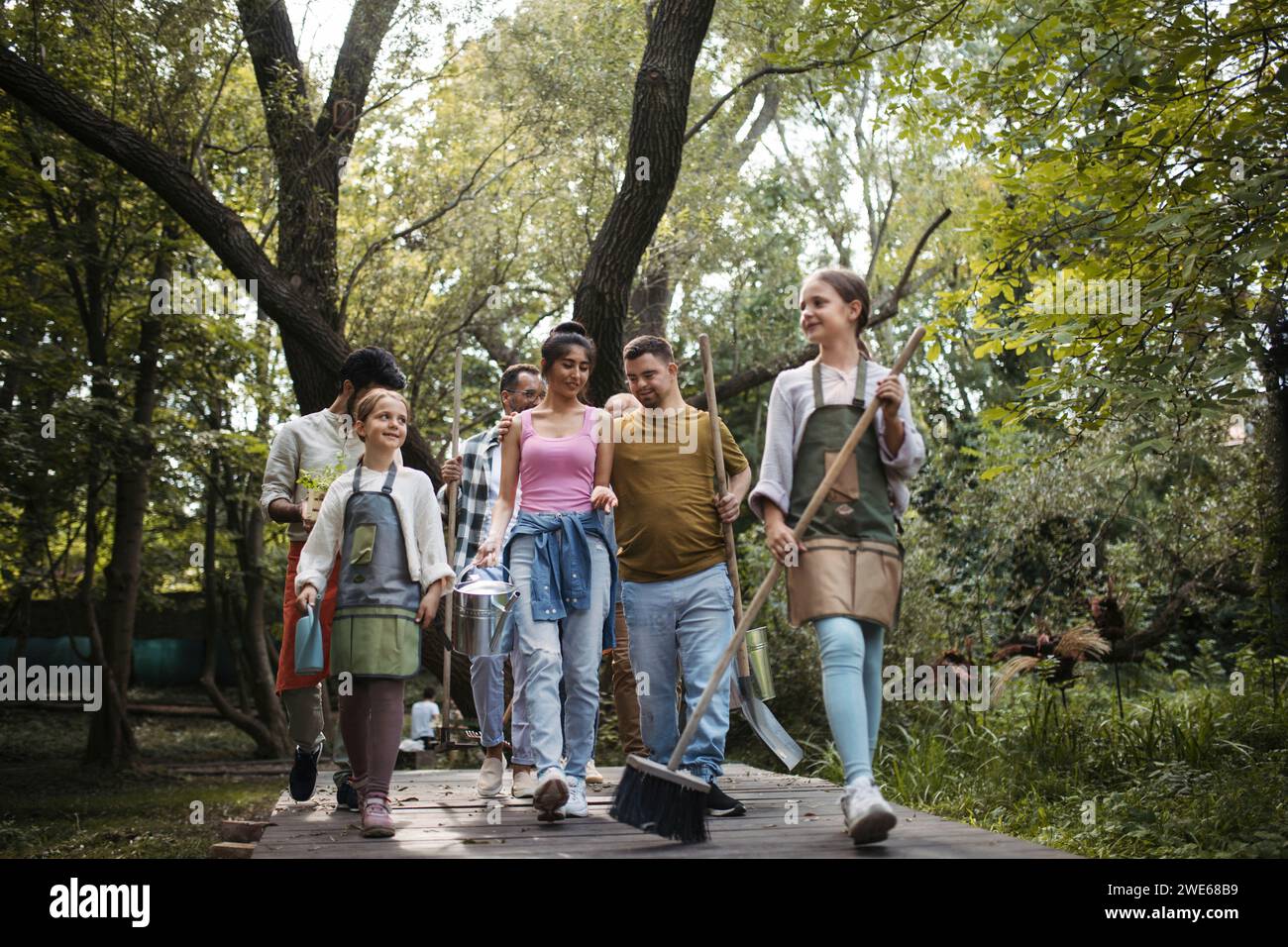 Group of volunteers with brooms and buckets taking part in community ...