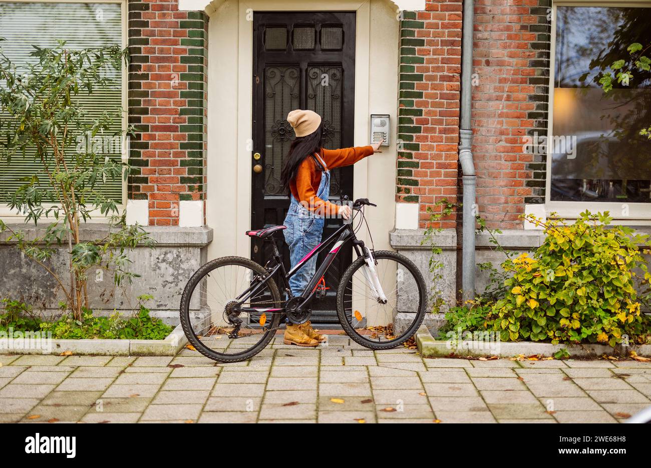 Woman with bicycle entering pin on door security system Stock Photo - Alamy