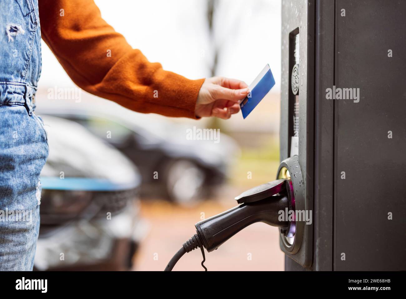 Woman paying with credit card at electric car charging station Stock ...