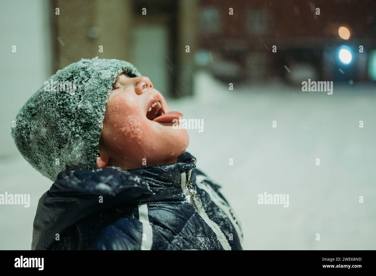 Happy boy catching snow with tongue in winter Stock Photo - Alamy