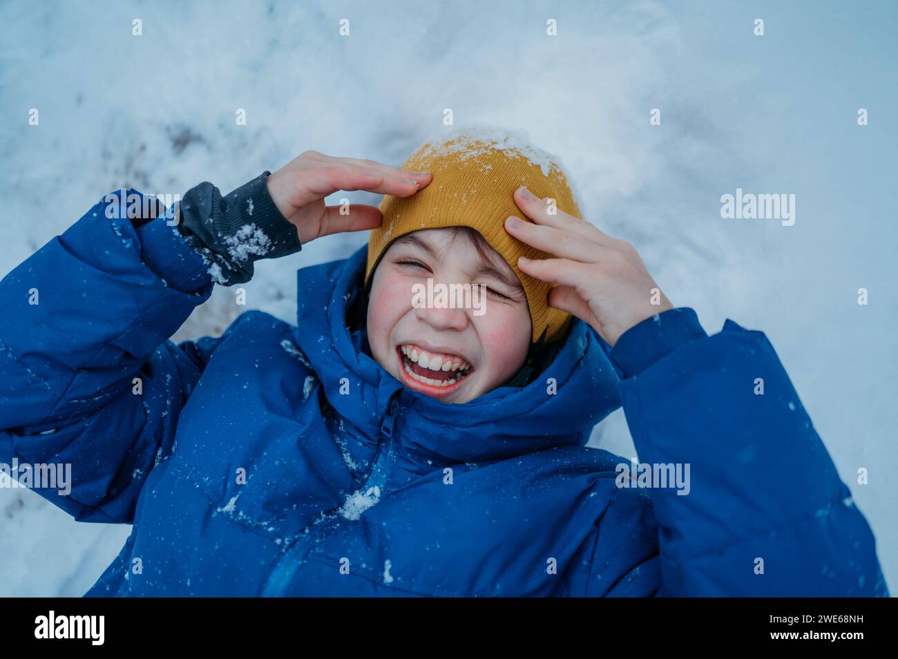 Happy boy lying on snow and laughing in winter Stock Photo - Alamy