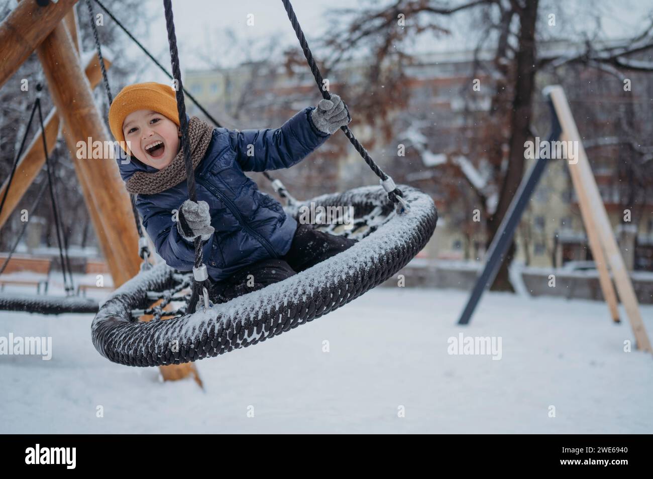 Happy boy swinging on nest swing in winter park Stock Photo - Alamy