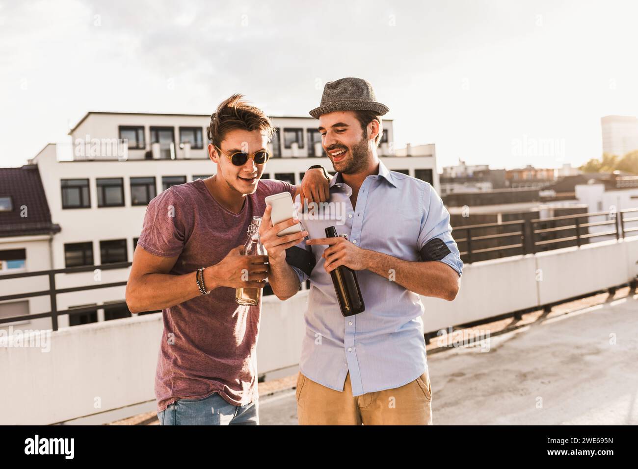 Happy man showing smart phone to friend on rooftop Stock Photo - Alamy